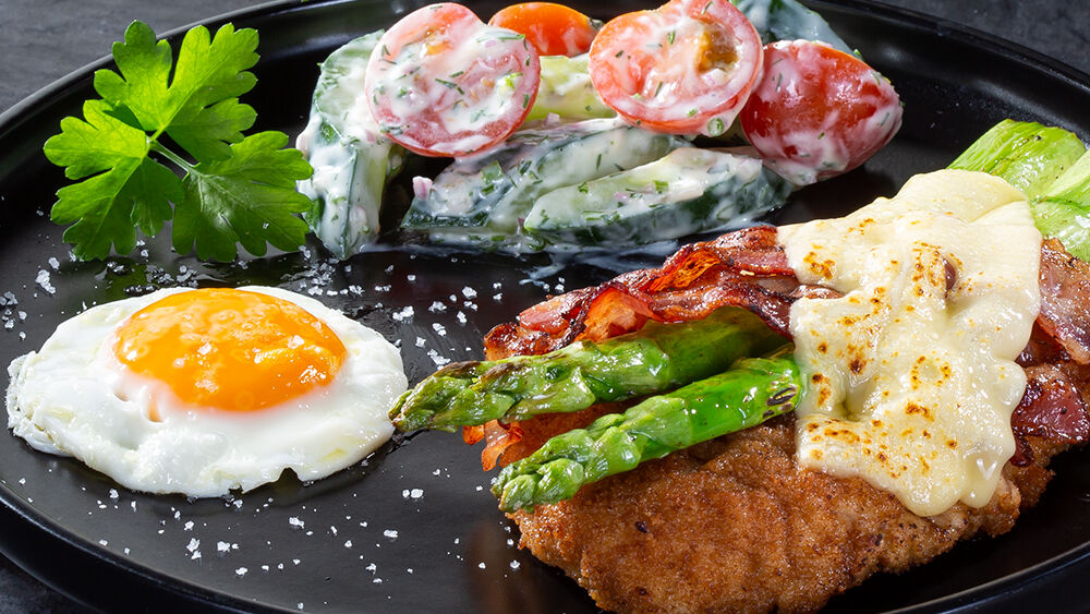 Panierte Schinkenschnitzel mit Bacon, grünem Spargel und Käse überbacken | Rezepte | HIT